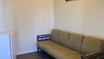 Quarto com sofá, uma pequena mesa branca e um quadro na parede.