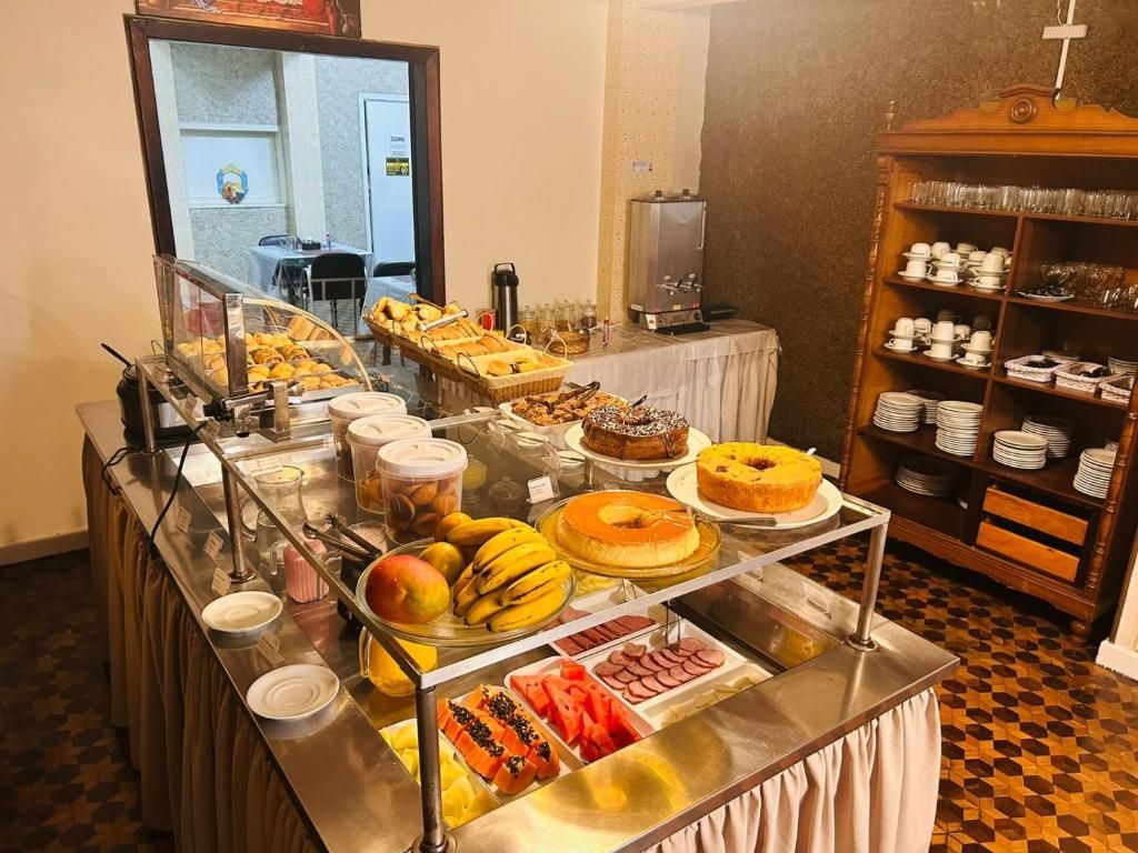 Buffet com diversos alimentos, máquina de café e suporte para copos.