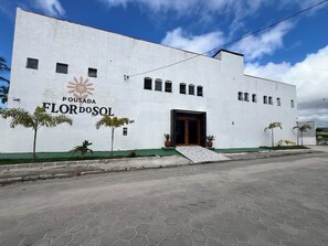 Edifício branco com a placa 'Pousada Flor do Sol' e uma escadaria que leva à entrada.
