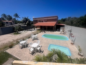 Zona residencial com piscina, área de estar ao ar livre e um edifício com telhado vermelho.