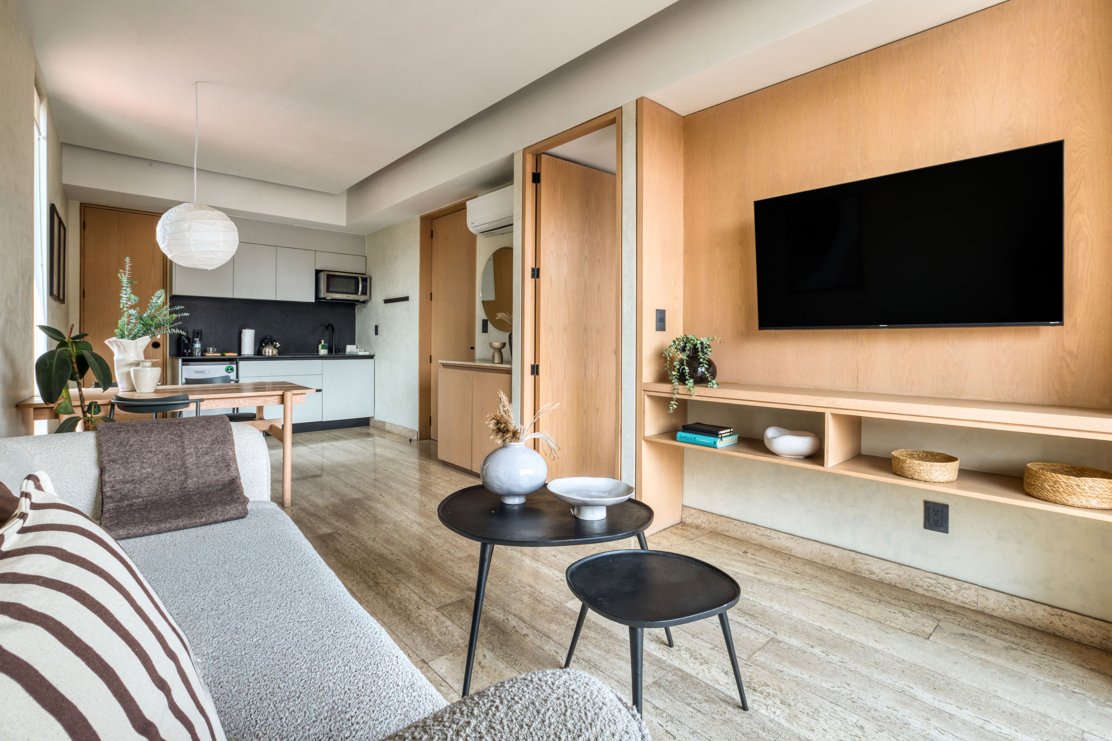 Uma sala de estar moderna com um sofá, uma mesa de jantar e uma TV na parede.