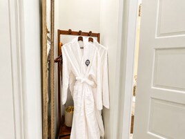 Corredor com moldura de porta de madeira e um roupão branco pendurado em um cabide de madeira.