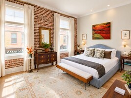 Quarto com cama grande, cômoda, espelho e pintura na parede.