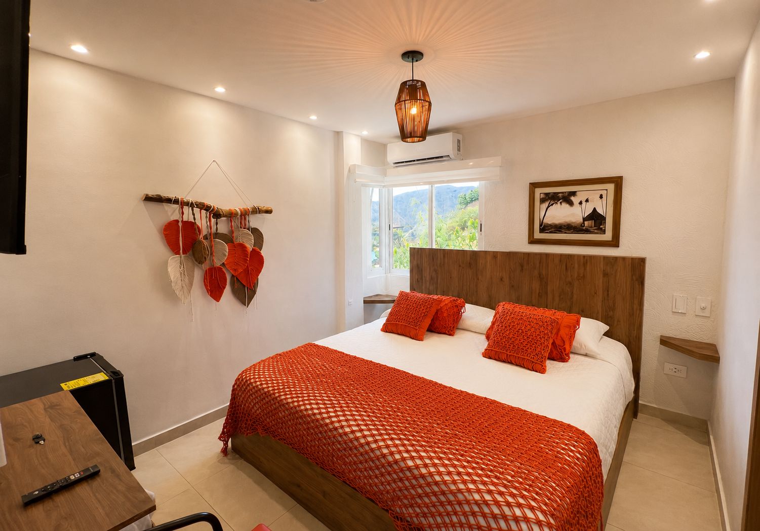 Quarto com cama, cabeceira de madeira, ar condicionado fixado na parede, janela com vista e decoração na parede.