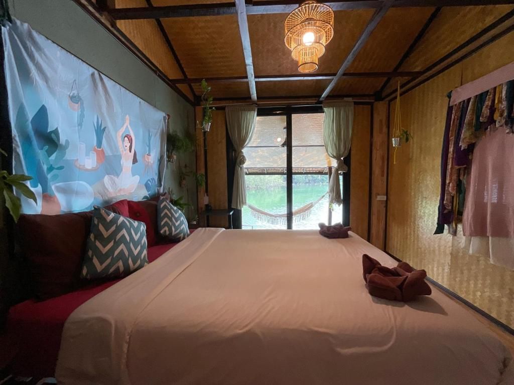 Quarto com cama grande, luminária pendente, rede e vista para o exterior.
