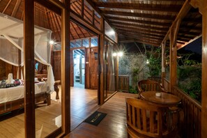 Interior de madeira com uma cama, uma mesa e um banco.