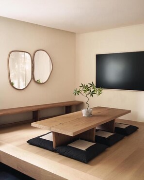Quarto minimalista com mesa de madeira, bancos e planta em vaso.
