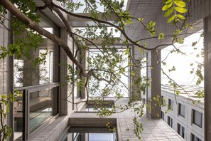 Um edifício moderno com fachada de vidro, uma árvore em primeiro plano e vista do céu.