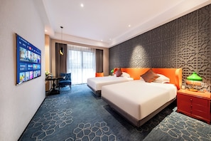 Quarto de hotel com duas camas, uma escrivaninha, uma cadeira, uma TV e parede com padrão.
