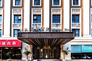 Um hotel com fachada moderna, entrada coberta e placas em chinês e inglês.