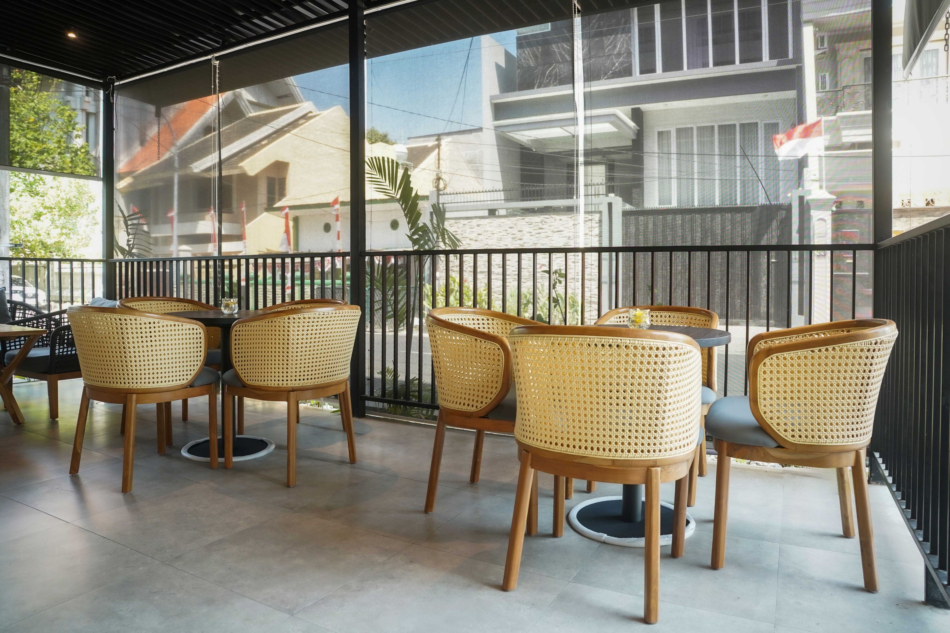 Restaurante com área externa, mesas redondas e cadeiras de vime.