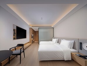 Quarto de hotel moderno com uma cama grande, uma mesa e uma cadeira.