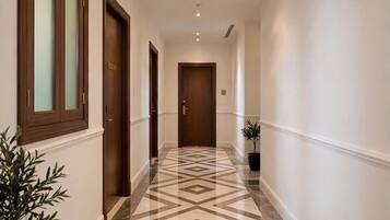 Um corredor com piso estampado, portas e um vaso de planta.