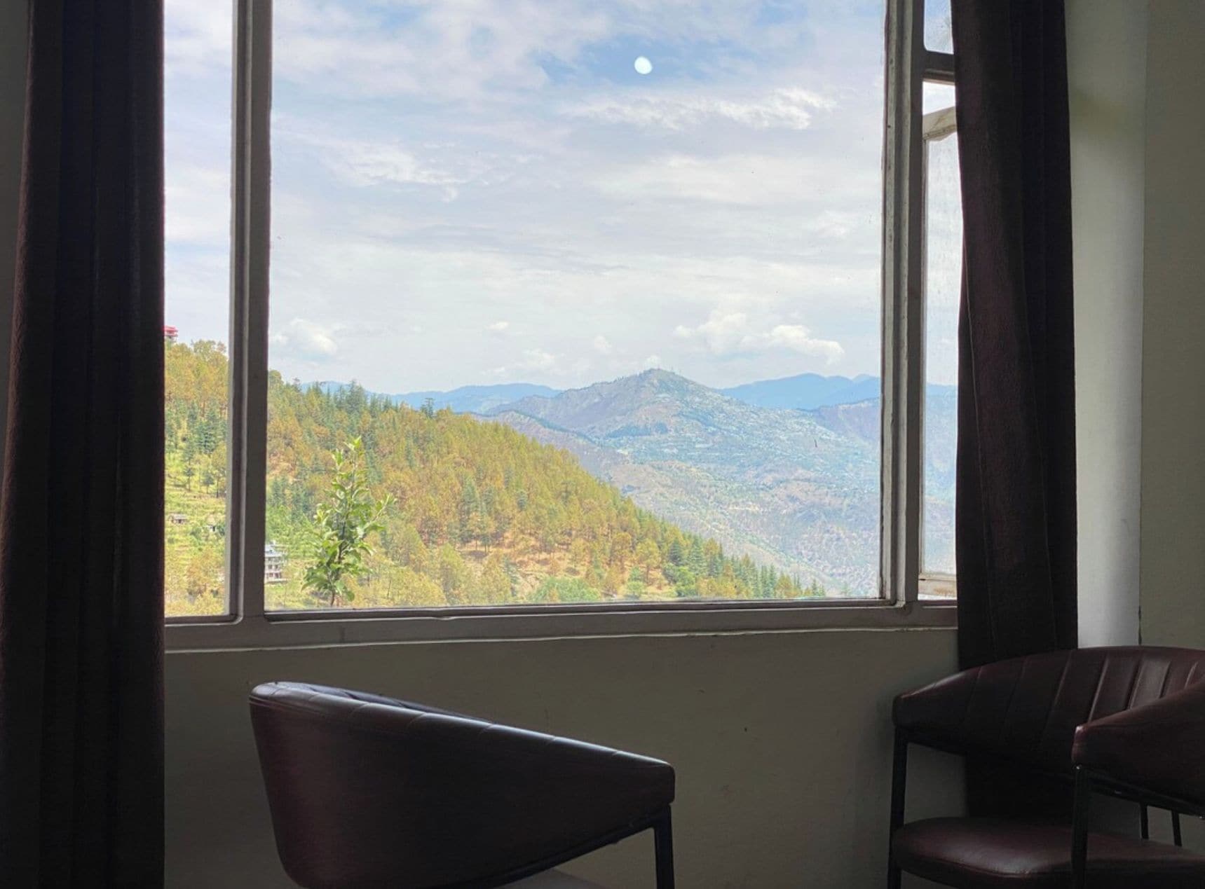 Quarto com uma grande janela que oferece vista para uma paisagem montanhosa.