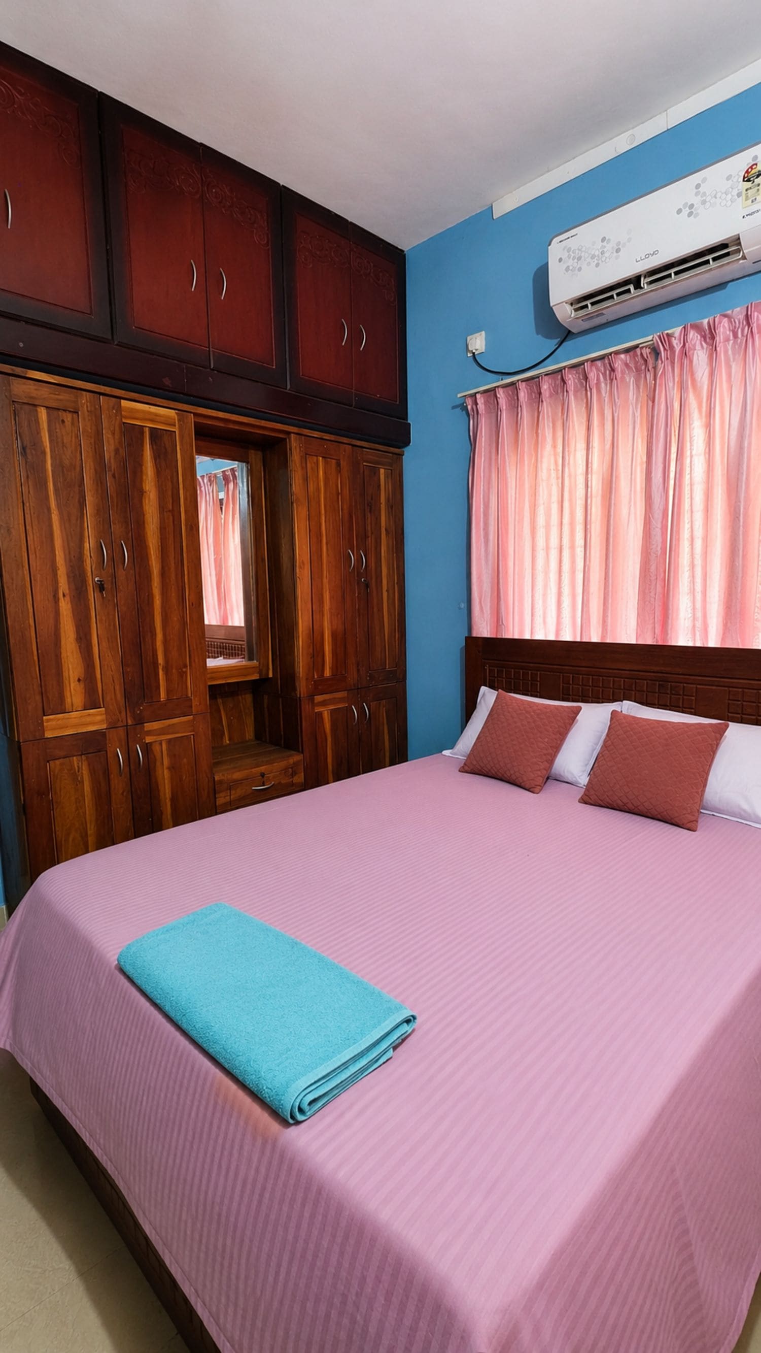 Quarto com cama, guarda-roupa de madeira e ar condicionado.