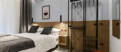 Quarto de hotel com cama, guarda-roupa, mesa de cabeceira e espelho.