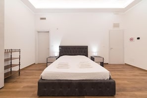 Quarto com cama, mesas de cabeceira, guarda-roupa e escada.