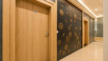 Corredor com portas de madeira, numeradas 302, e uma parede com desenhos circulares.