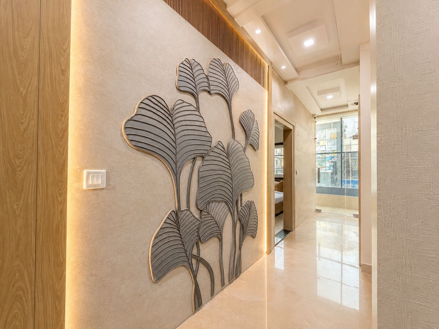 Corredor com design moderno na parede, porta de madeira e vista para um quarto com cama e janela.