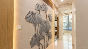 Corredor com design moderno na parede, porta de madeira e vista para um quarto com cama e janela.