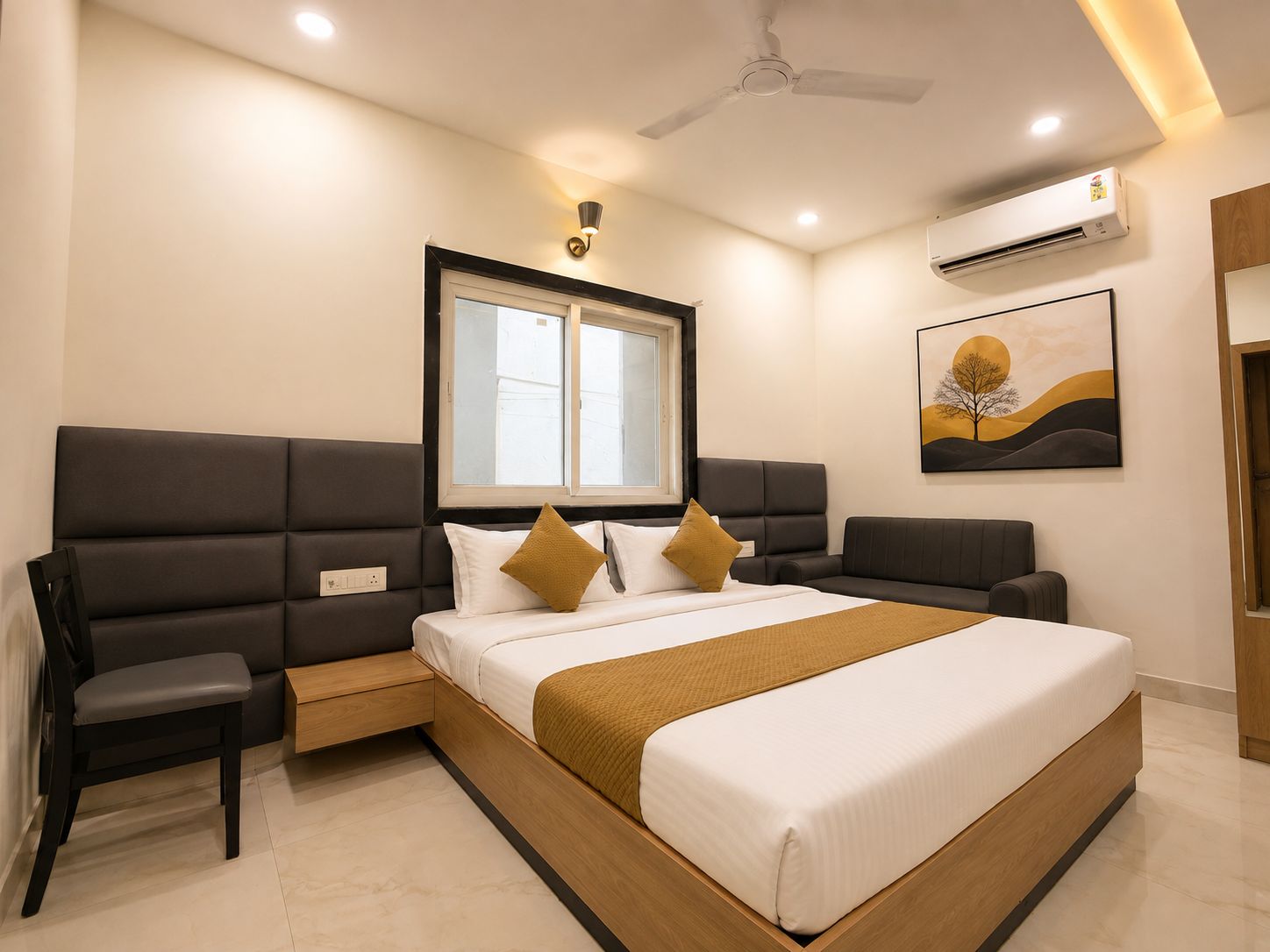 Quarto com cama, área de estar, janela, ar-condicionado e ventilador de teto.
