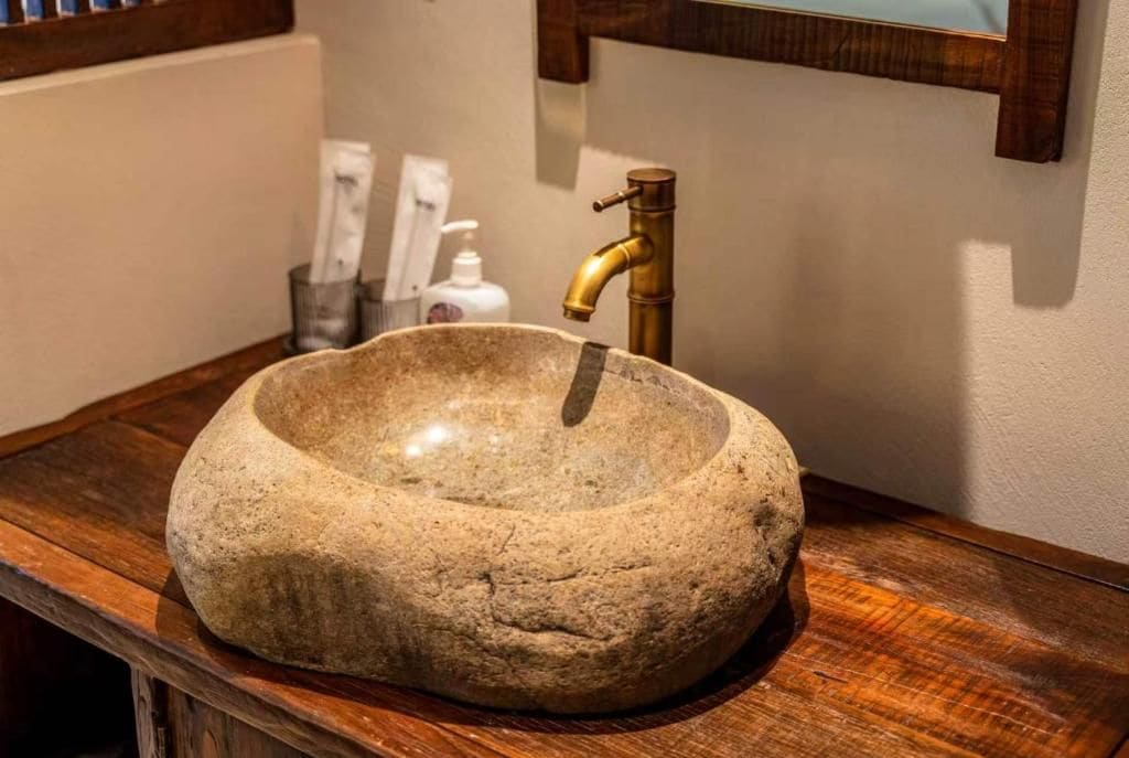 Uma pia de pedra com torneira de latão em um banheiro.
