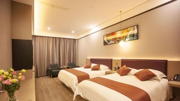 Quarto de hotel com duas camas, uma escrivaninha, uma cadeira, uma televisão e um quadro na parede.