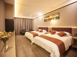 Quarto de hotel com duas camas, uma escrivaninha, uma cadeira, uma televisão e um quadro na parede.