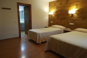 Quarto de hotel com duas camas, painel de cabeceira em madeira, abajures e piso de madeira.