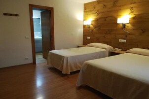 Quarto de hotel com duas camas, painel de cabeceira em madeira, abajures e piso de madeira.