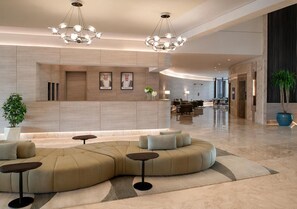Um lobby moderno com área de estar curvo, balcão de recepção e uma grande planta em vaso.