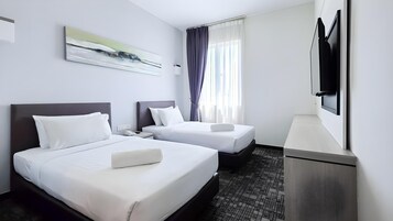 Quarto de hotel com duas camas, televisão de tela plana, um quadro na parede e uma janela com cortinas.