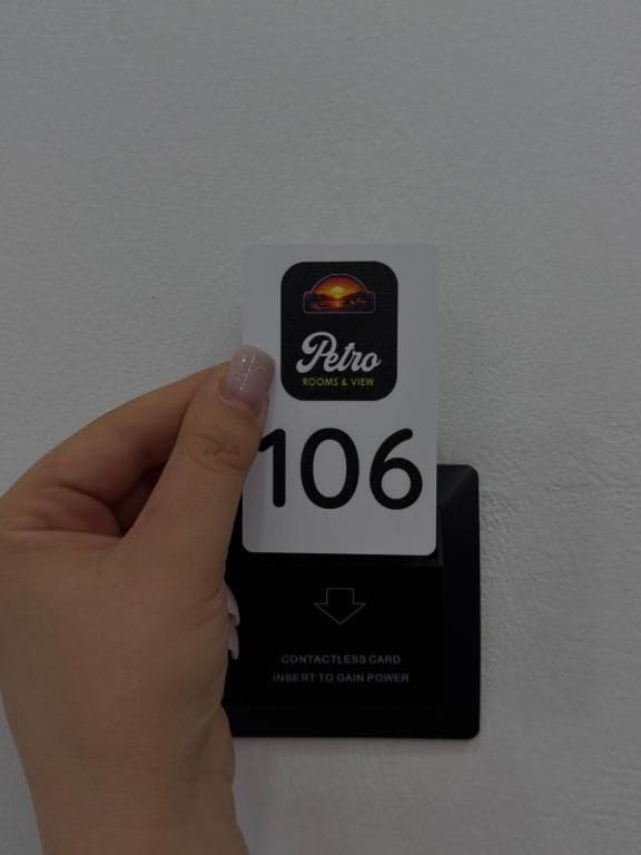 Mão segurando um cartão sem contato com o número 106 e o nome 'Petro', inserido em um leitor de cartão.