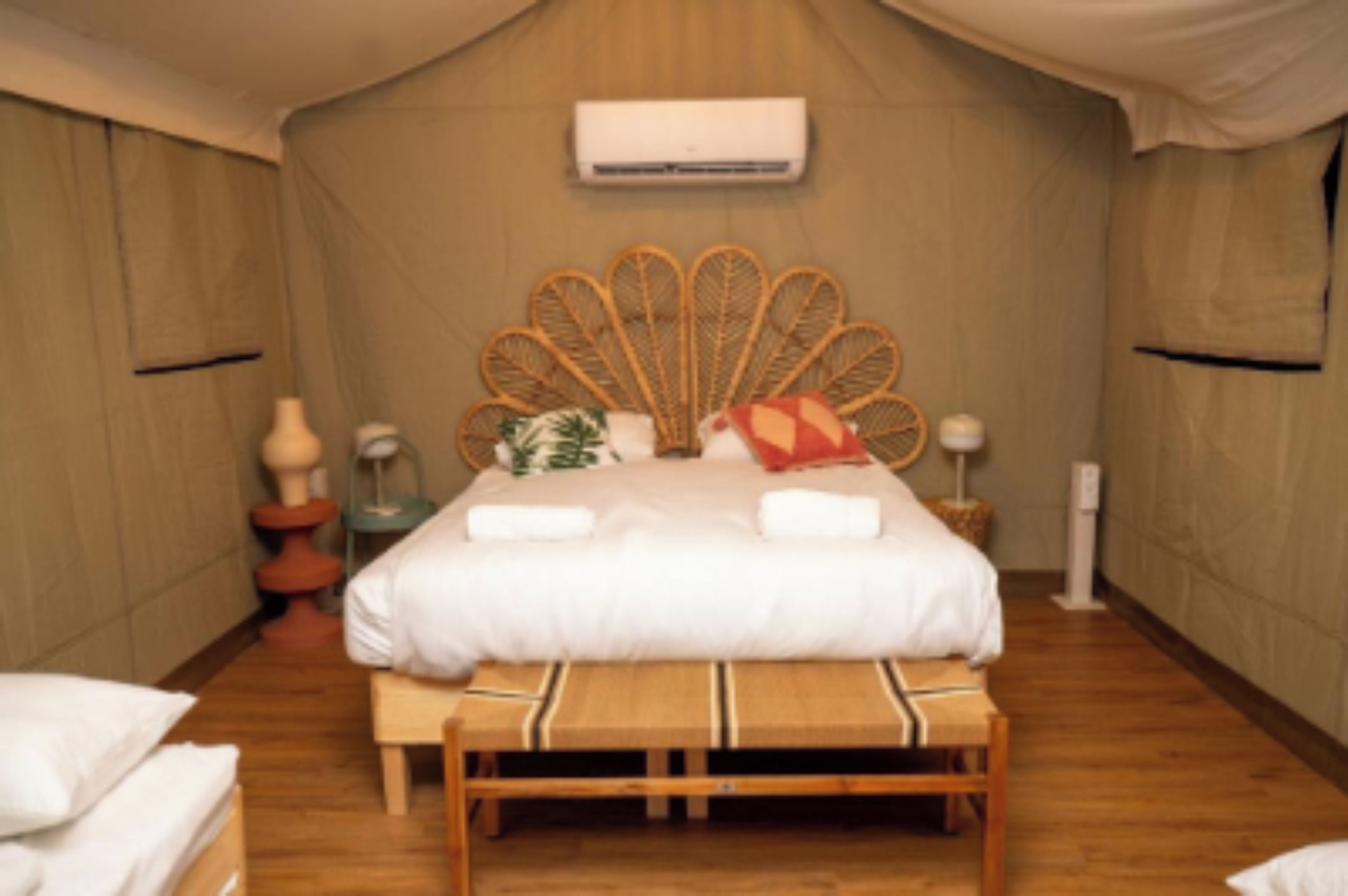 Quarto com cama, mesas de cabeceira, ar condicionado e painel decorativo na parede.