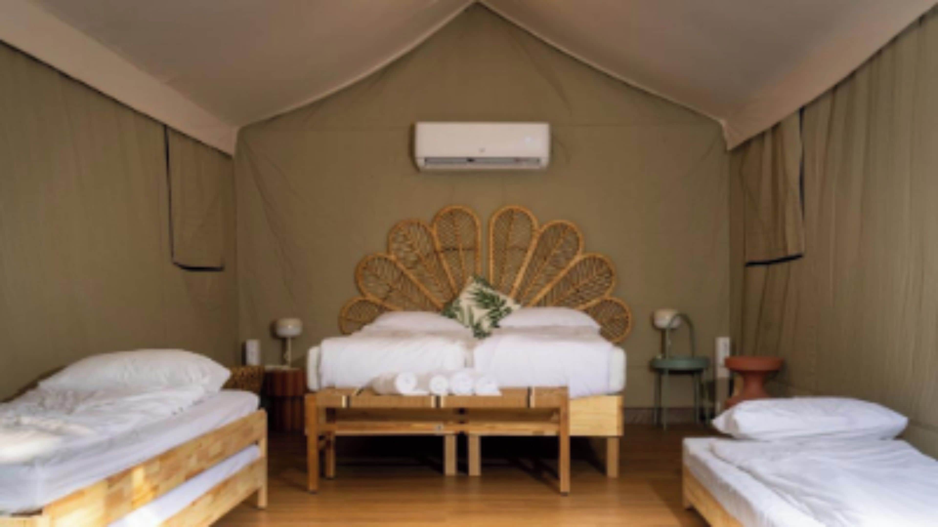 Quarto com cama, mesa de cabeceira, luminária e ar condicionado.