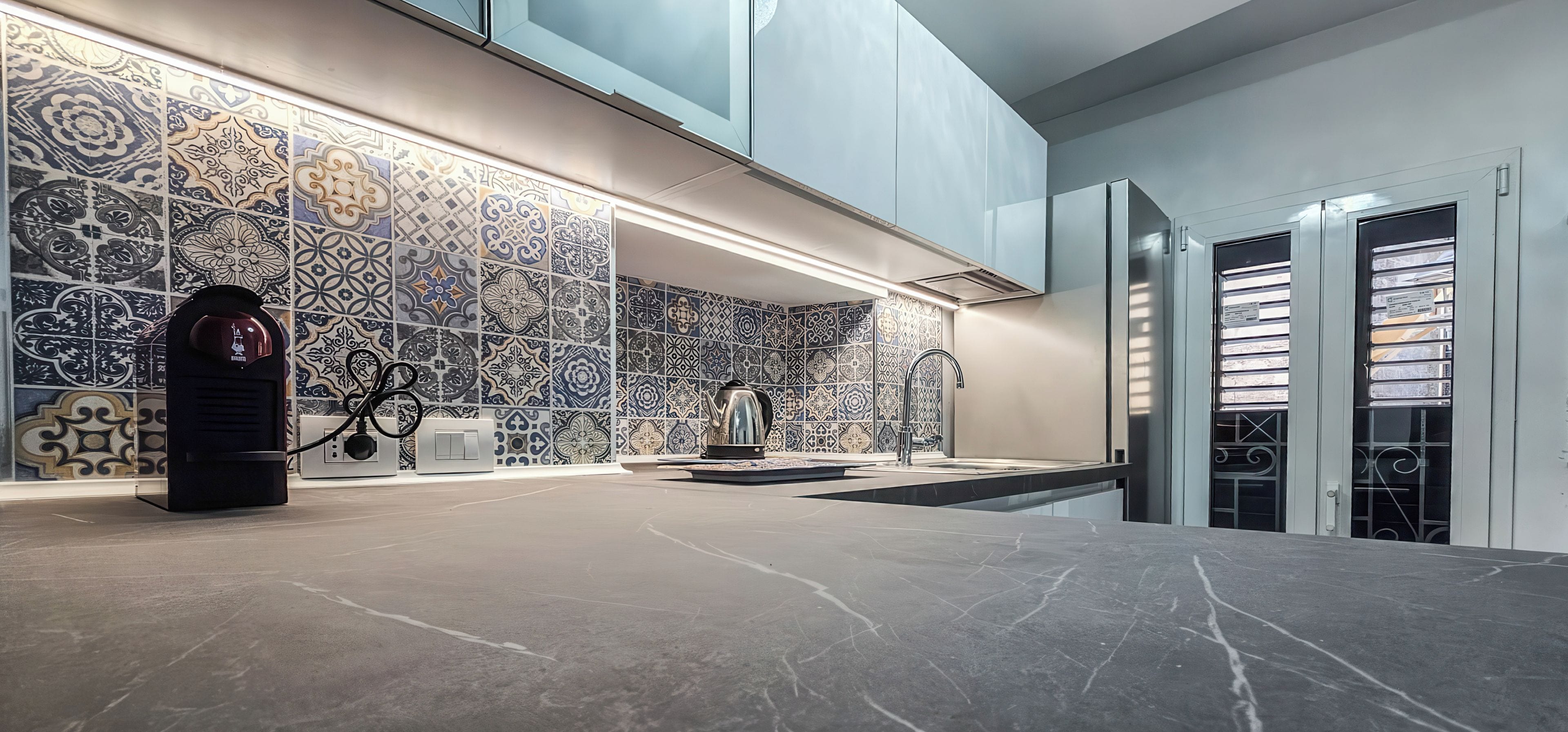 Cozinha moderna com azulejos estampados, máquina de café e pia.