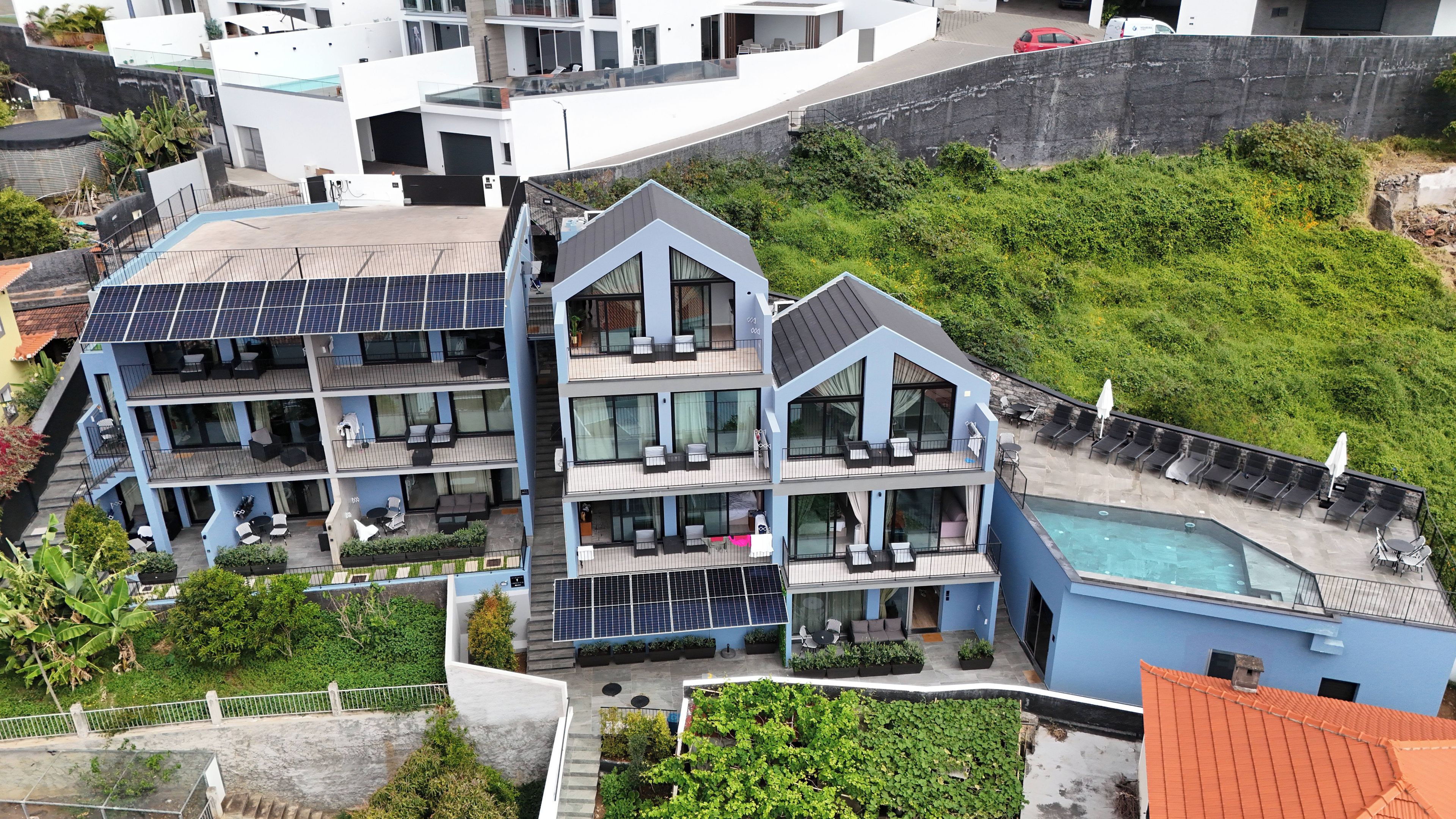Um hotel com vários andares, varandas, piscina e painéis solares.