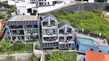 Um hotel com vários andares, varandas, piscina e painéis solares.