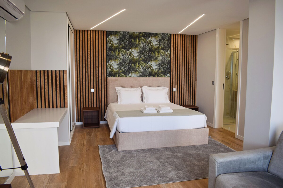 Quarto moderno com uma cama grande, uma escrivaninha e zona de chuveiro.