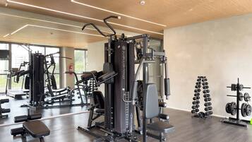 Uma academia com diversos equipamentos de exercício, incluindo um suporte para agachamentos, bancos e halteres.