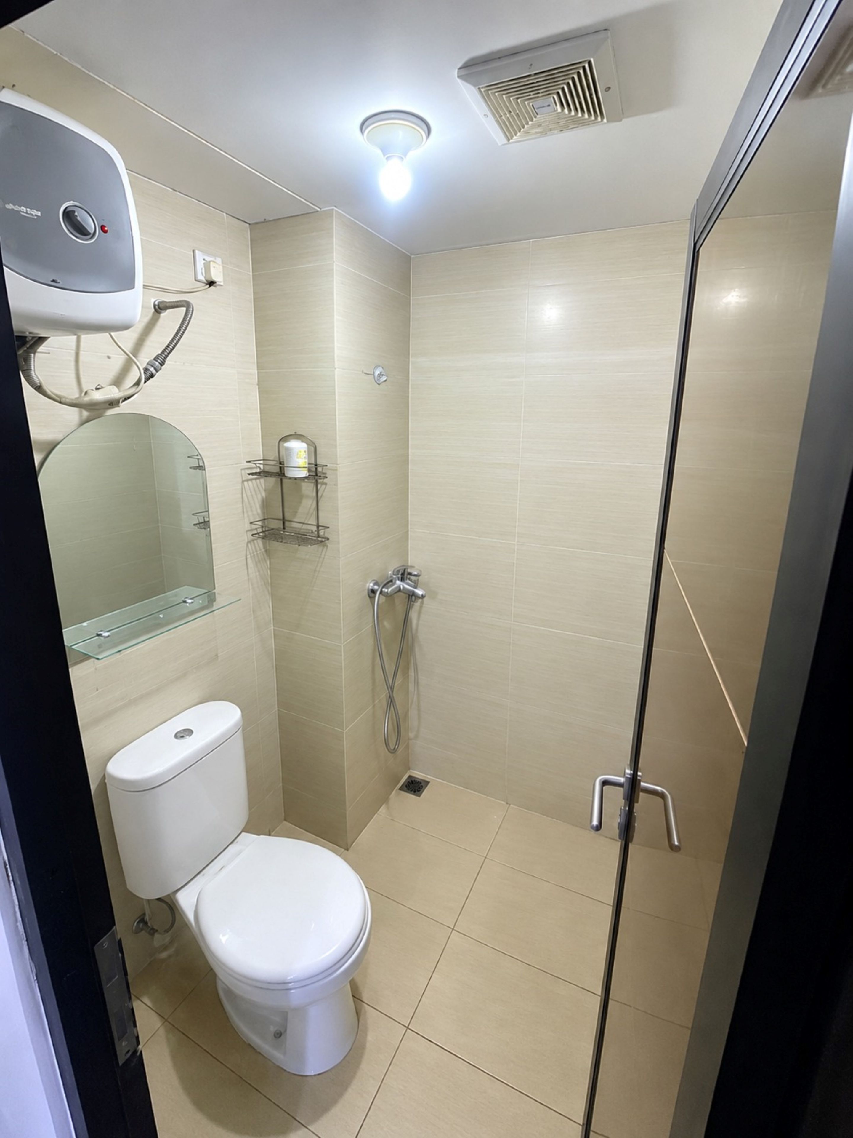 Casa de banho moderna com sanita, cabine de duche em vidro e secador de cabelo fixo.