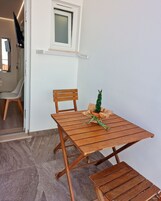 Uma mesa de madeira com cadeiras, uma pequena janela e um vaso com planta.