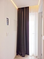 Quarto com porta, interruptor de luz e vista parcial de uma cortina.