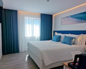 Quarto de hotel moderno com uma cama grande, cortinas azuis e um quadro na parede.