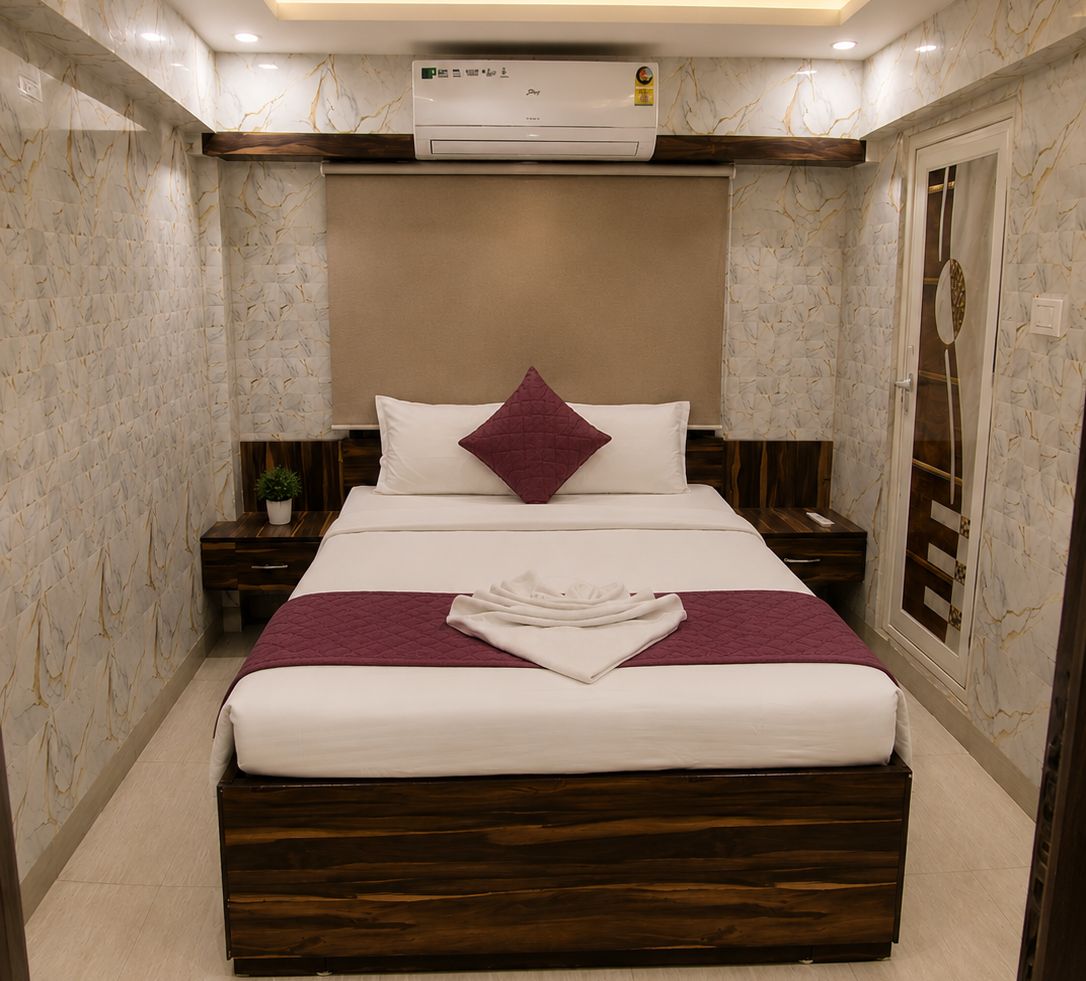 Quarto de hotel com cama, mesas de cabeceira, ar condicionado fixado na parede e uma porta com espelho.