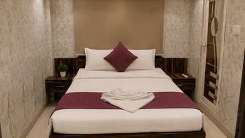 Quarto de hotel com cama, mesas de cabeceira, ar condicionado fixado na parede e uma porta com espelho.