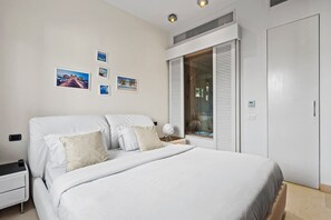 Quarto com cama, mesa de cabeceira, guarda-roupa e janela com persianas.