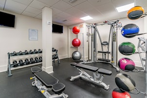 Uma academia com diversos equipamentos de exercício, incluindo halteres, bolas de medicina e aparelhos de musculação.