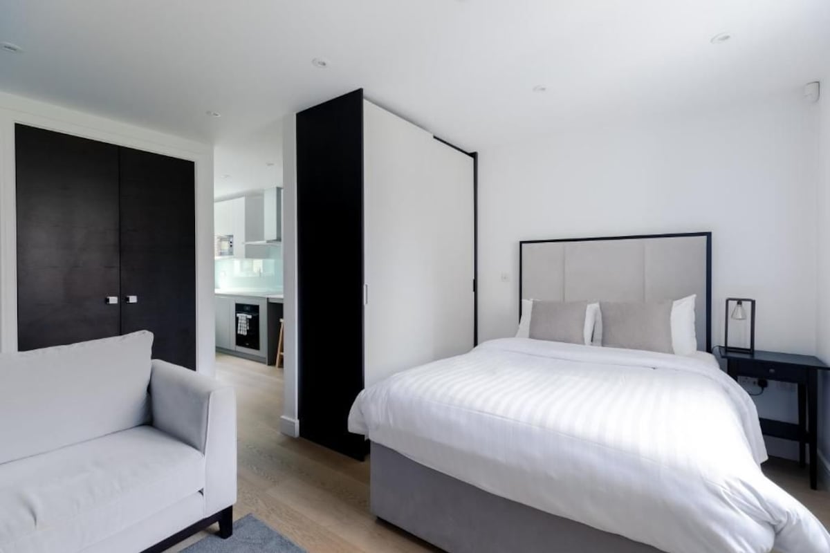 Quarto moderno com uma cama grande, um sofá e um guarda-roupa.