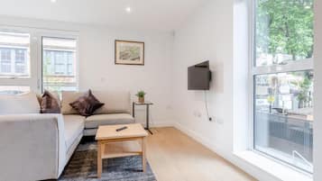 Uma sala de estar moderna com um sofá, uma mesa pequena e uma TV na parede.